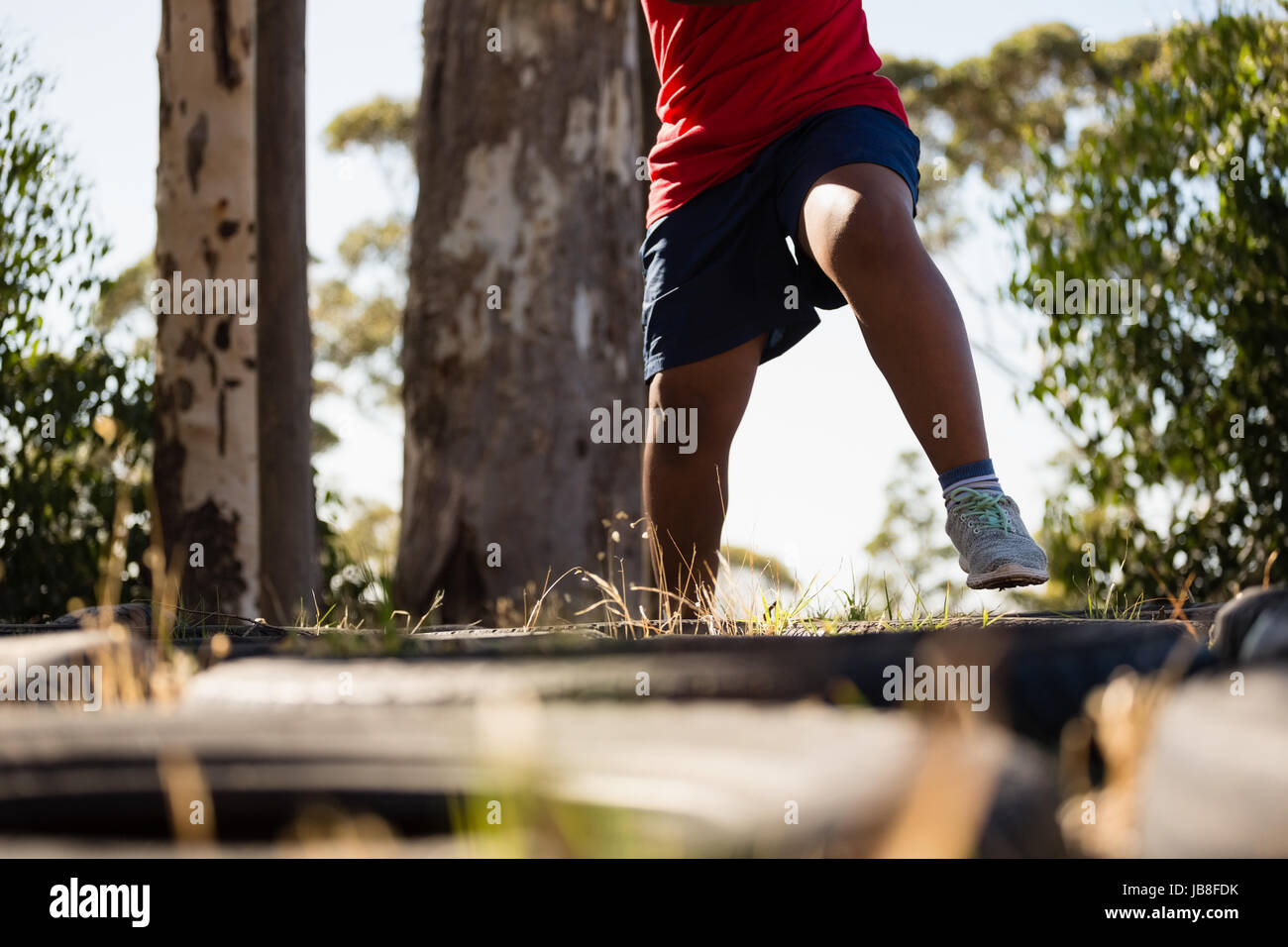 Boy running over tyres during obstacle course training in the boot camp ...