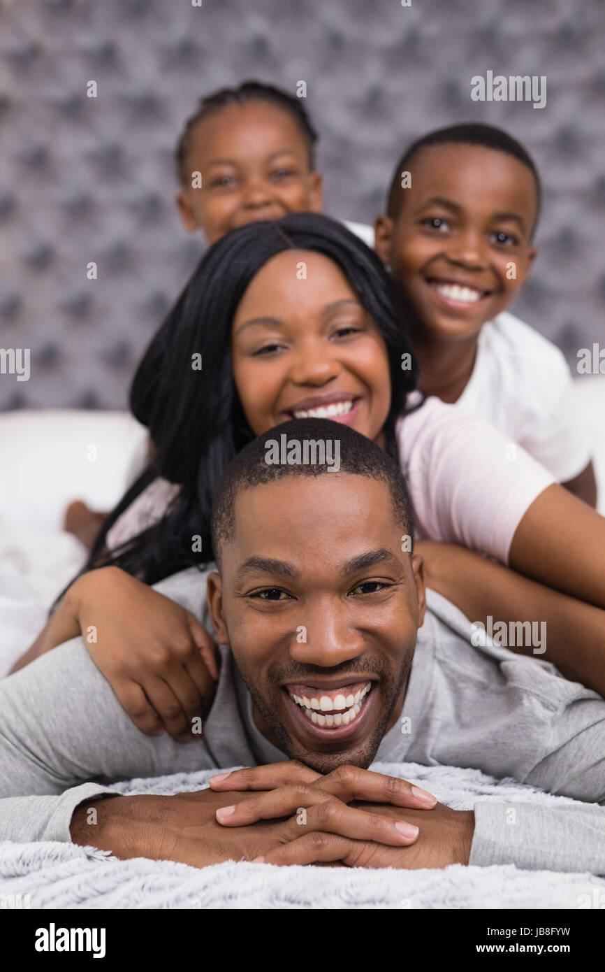 Portrait of smiling man with family lying together on bed at home Stock ...