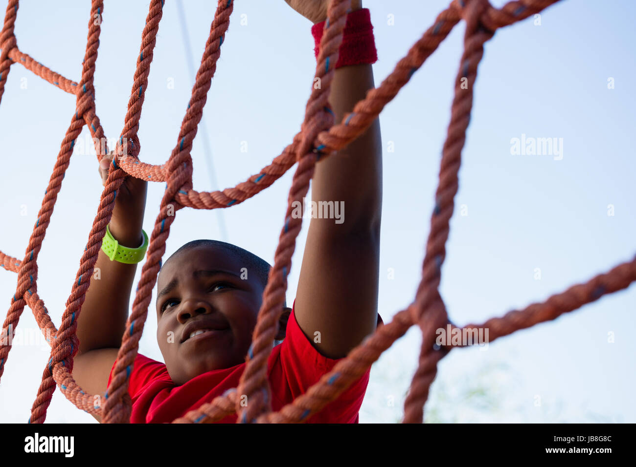 Boy climbing a net during obstacle course training in the boot camp ...