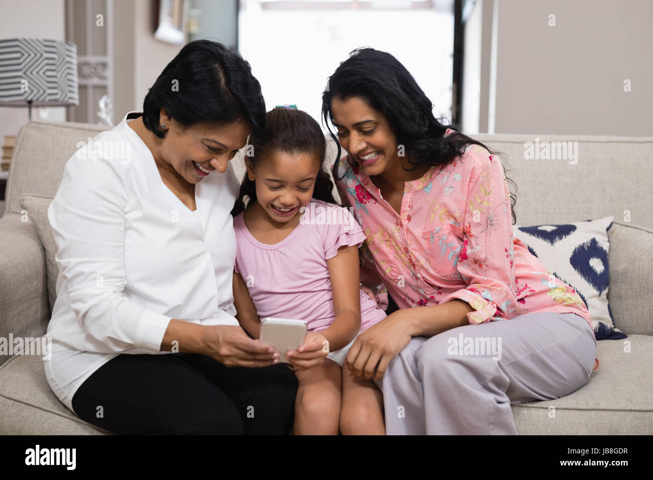Happy multi-generation family using mobile phone together while sitting ...