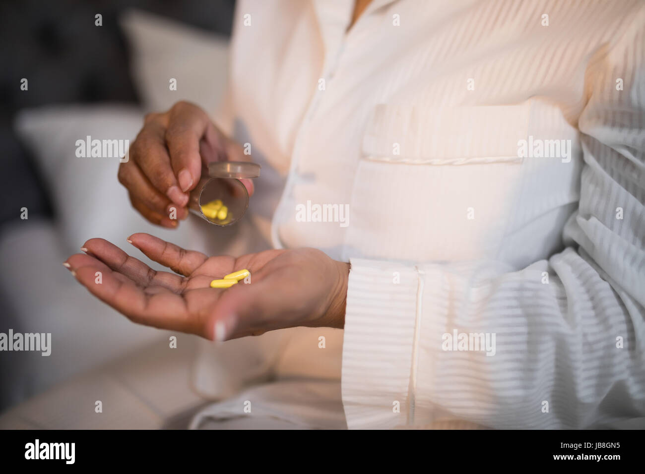 Mid section of woman taking pills in bedroom Stock Photo - Alamy