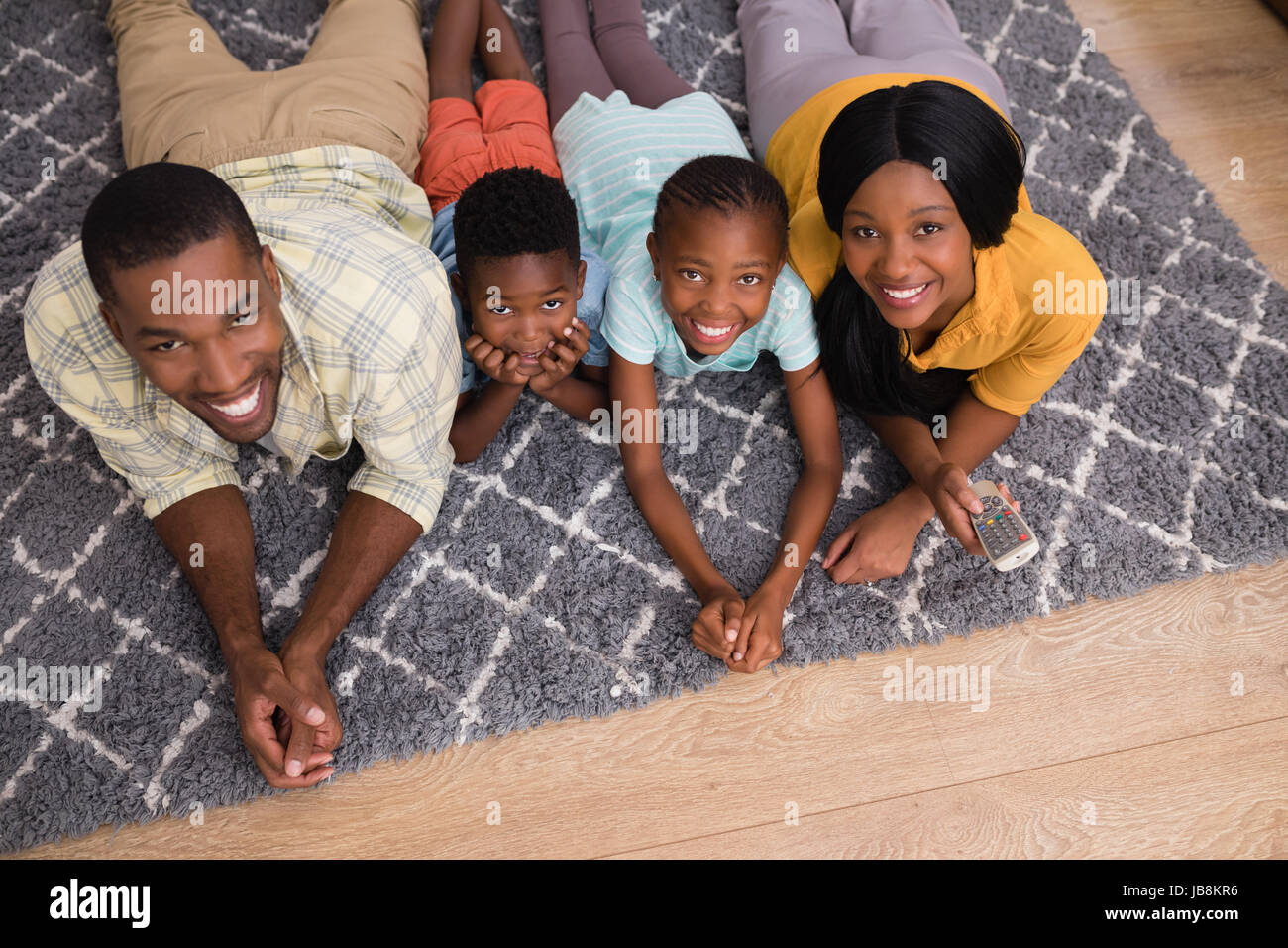 High angle portrait of smiling family lying on rug at home Stock Photo ...