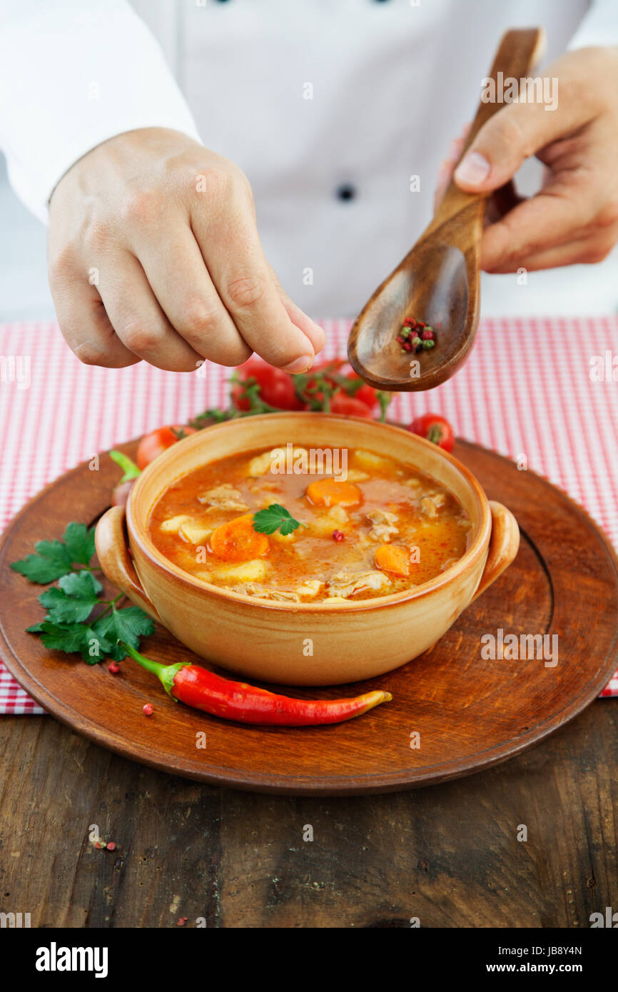 Hotel restaurant concept. Chef is finishing presenting stew dish with ...
