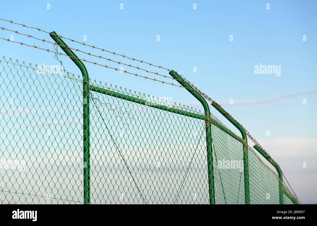 Mesh fence with barbed wire on a background of blue sky Stock Photo - Alamy