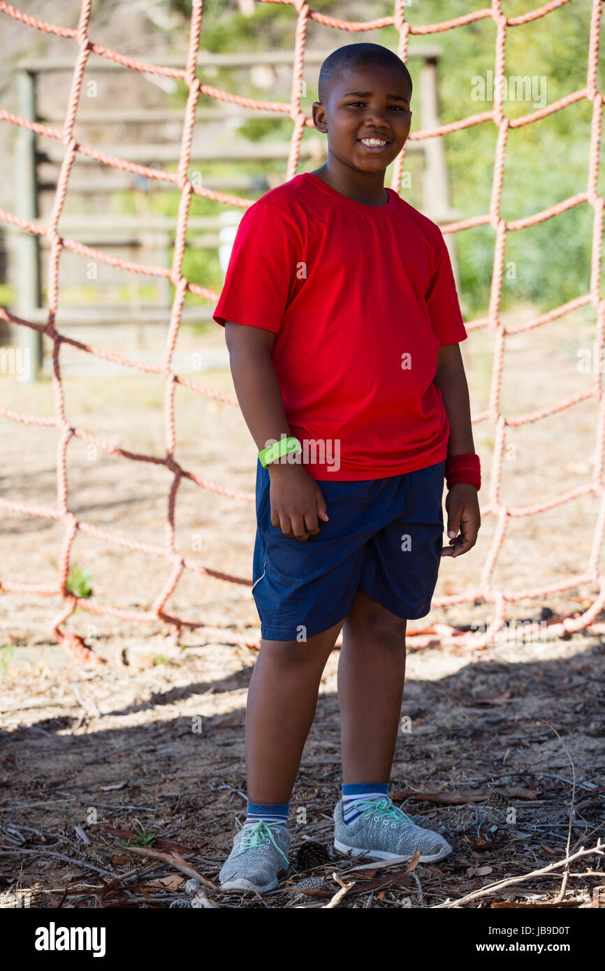 Portrait of boy standing in the boot camp during obstacle course ...