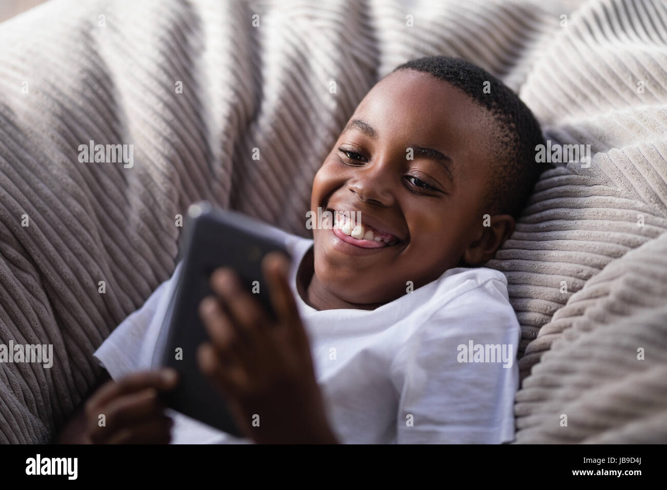 Little boy playing with phone on couch in living room at home Stock ...
