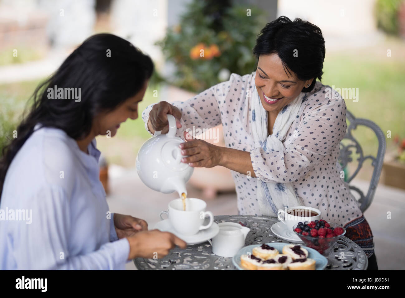 Smiling woman pouring tea in cup for daughter at home Stock Photo - Alamy