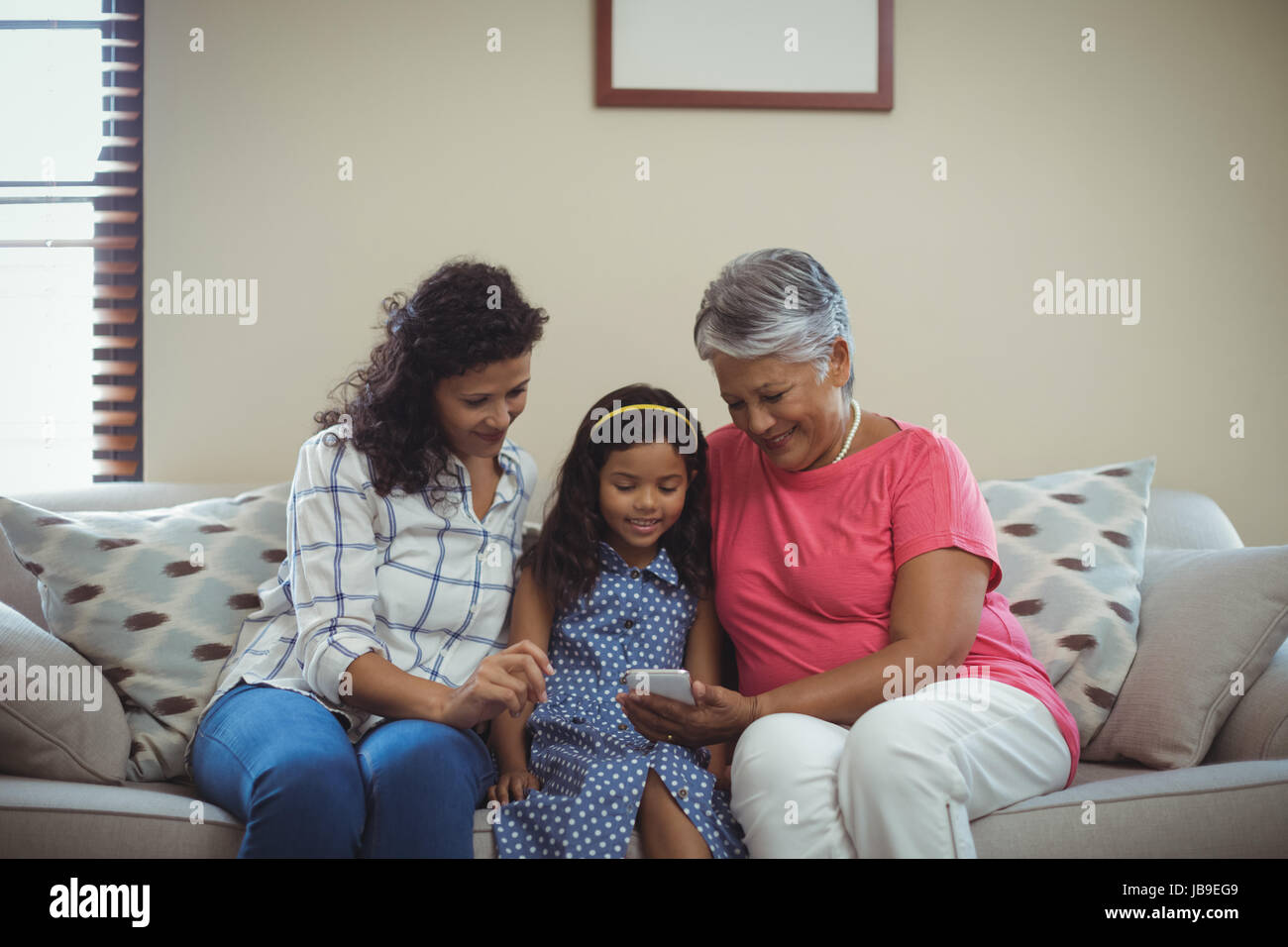Happy family using mobile phone in living room at home Stock Photo - Alamy