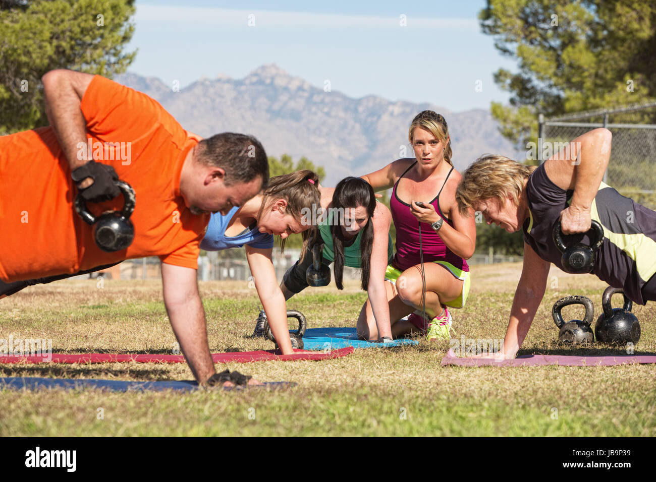 Young woman working with adults in boot camp fitness class Stock Photo ...