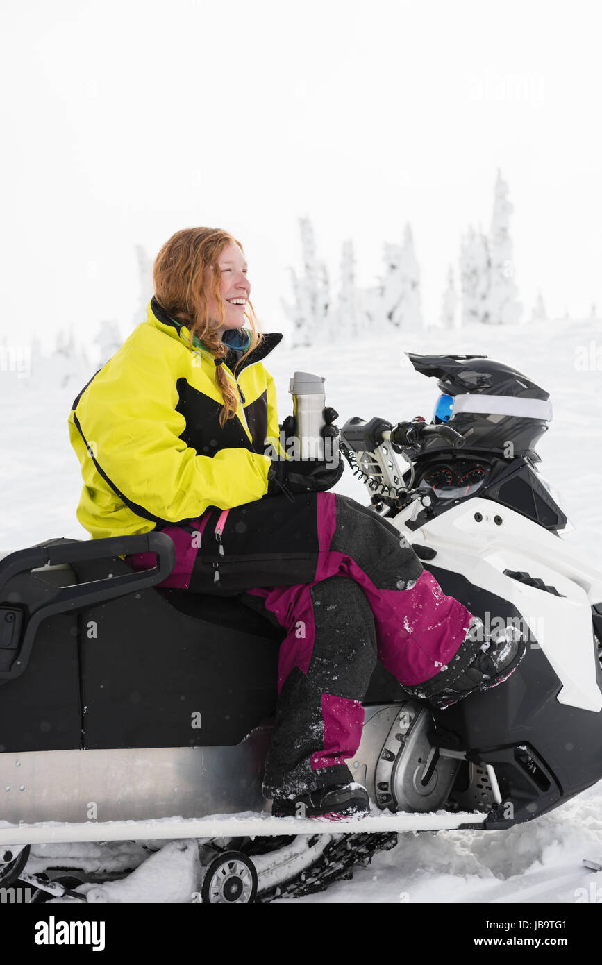 Woman sitting on snowmobile and having coffee during winter Stock Photo ...