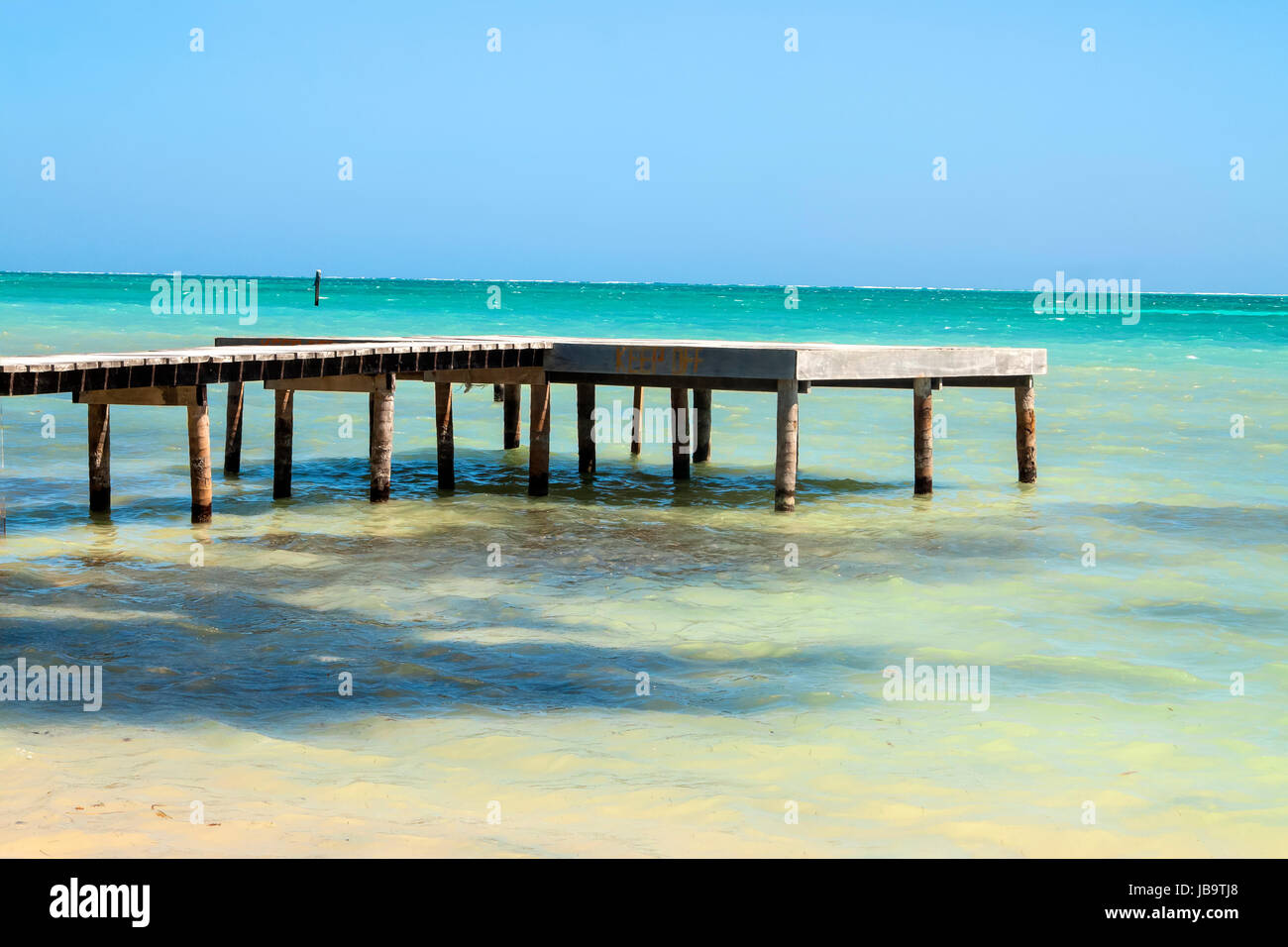 Beautiful tropical shoreline with pier for boats on the island of Caye ...