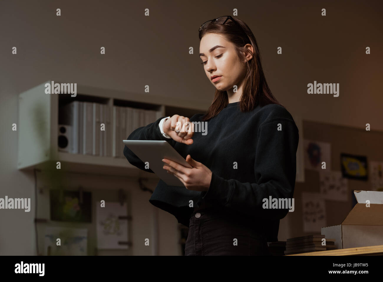 Female executive checking time while using digital tablet in office ...