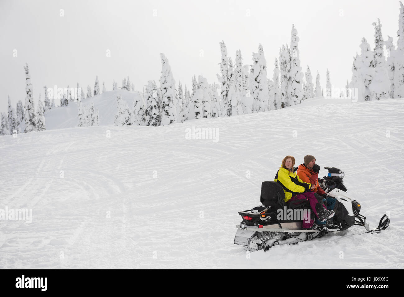 Couple sitting together on snowmobile during winter Stock Photo - Alamy