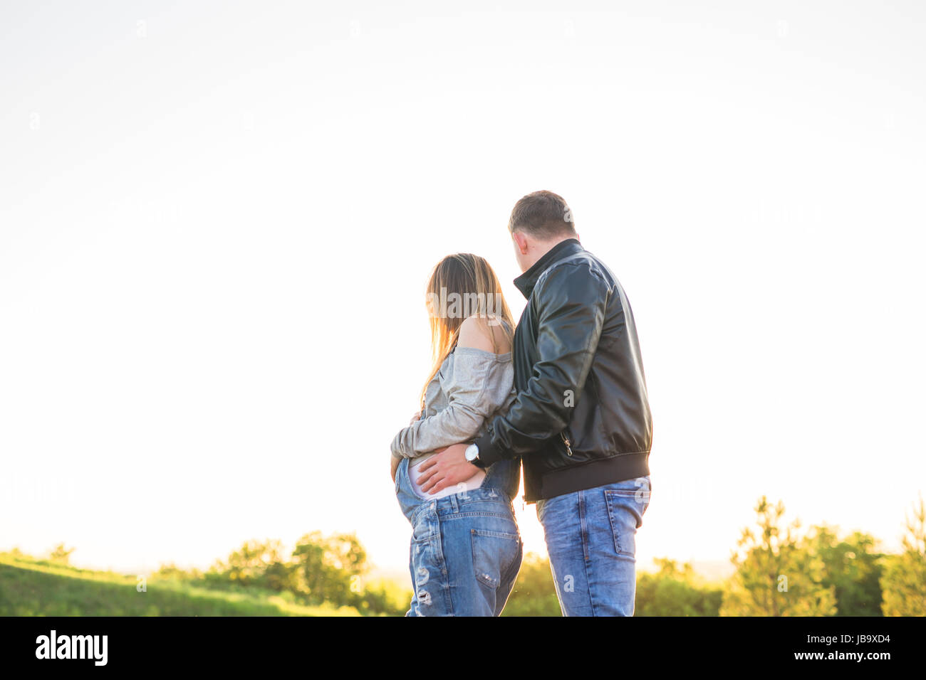 Happy young pregnant couple hugging in nature Stock Photo - Alamy