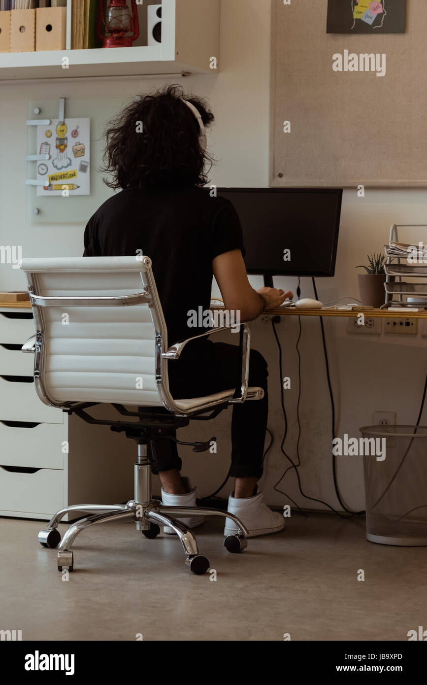 Rear view of male executive working on computer at desk in office Stock ...