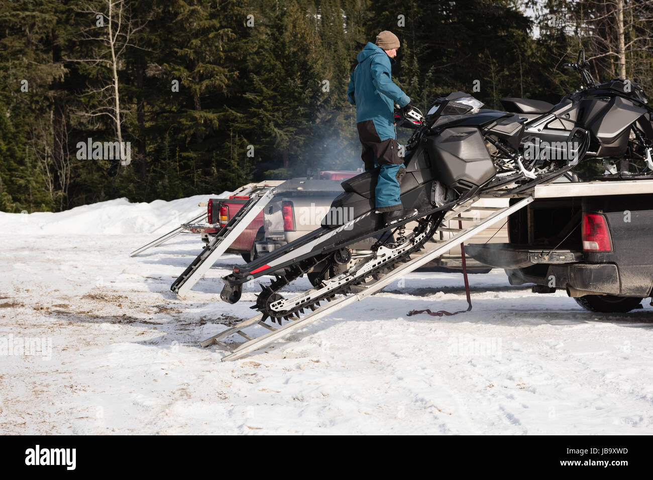 Man loading snowmobile on van during winter Stock Photo - Alamy