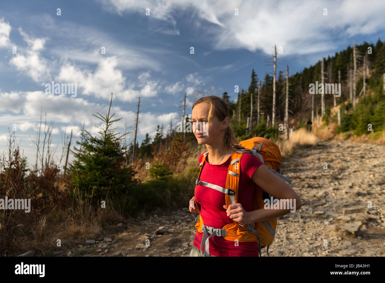 Pretty, female hiker going downhill in warm evening light Stock Photo ...