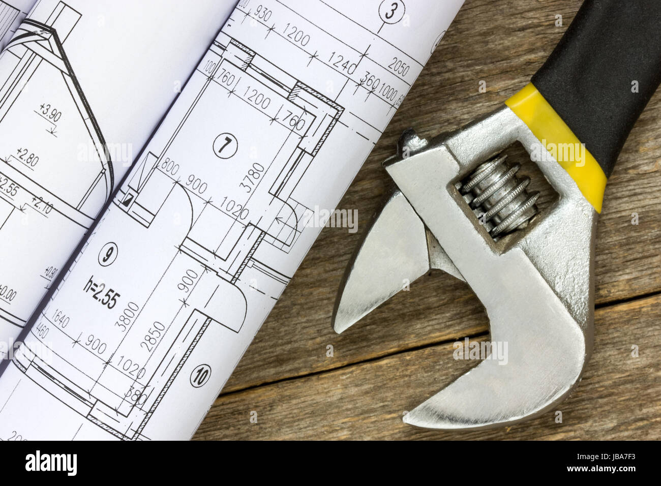 Twisted technical drawing and adjustable wrench on the wood background ...