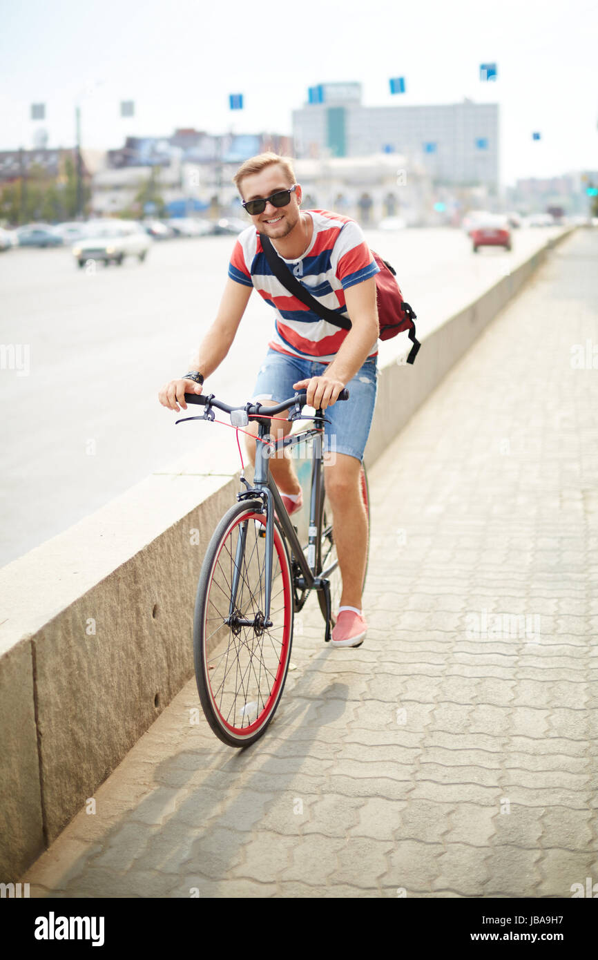 Portrait of happy guy riding bicycle in the city Stock Photo - Alamy