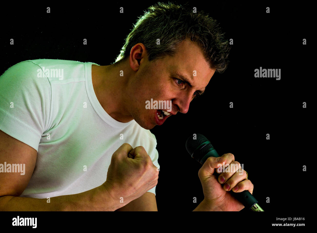 singer on stage screaming in a microphone. low key Stock Photo - Alamy