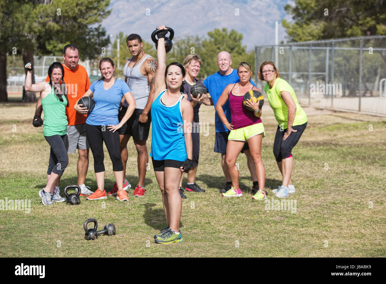 Happy woman lifting weights with group outdoors Stock Photo - Alamy