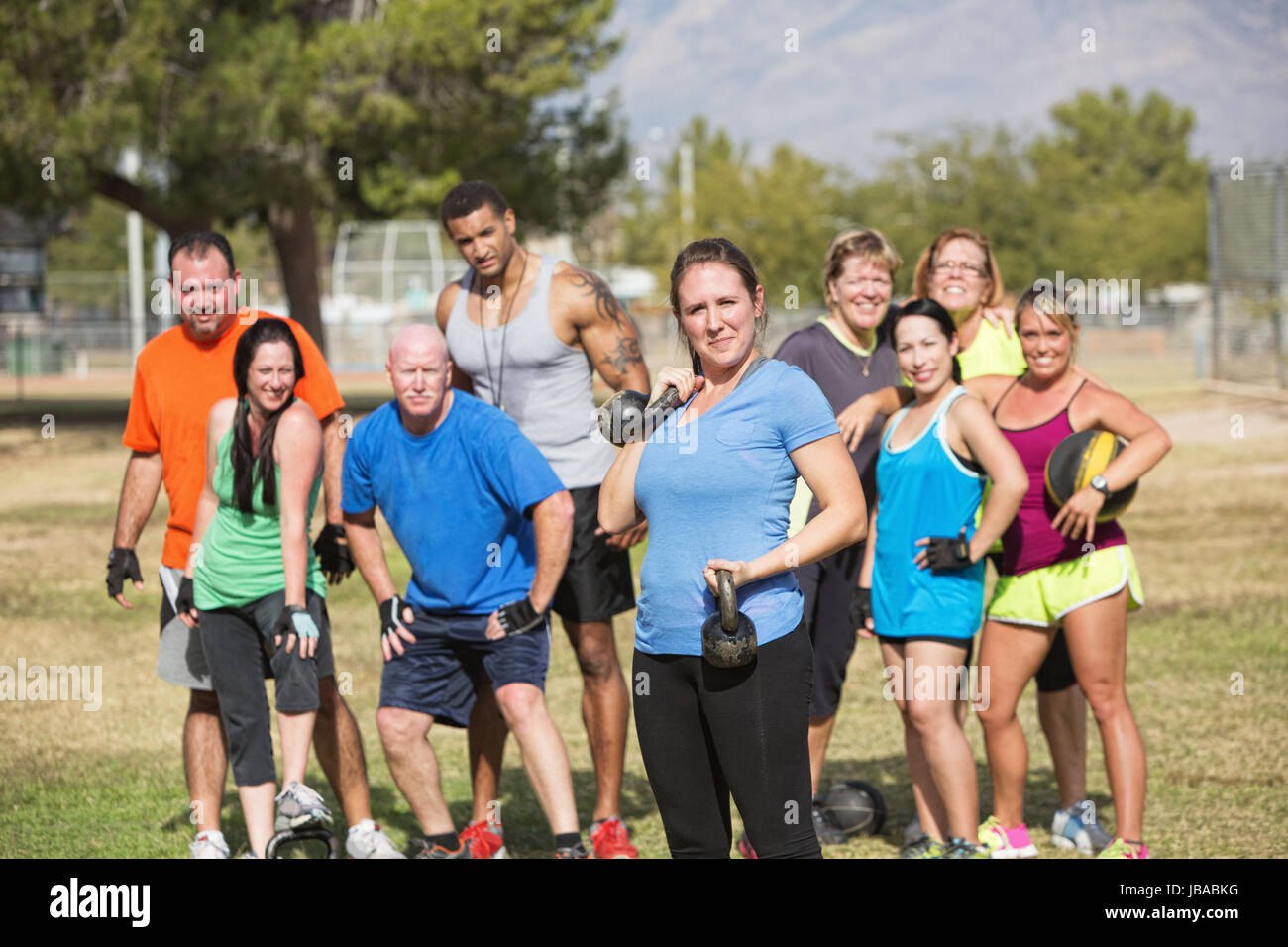 Confident young lady with group lifting weights outdoors Stock Photo ...