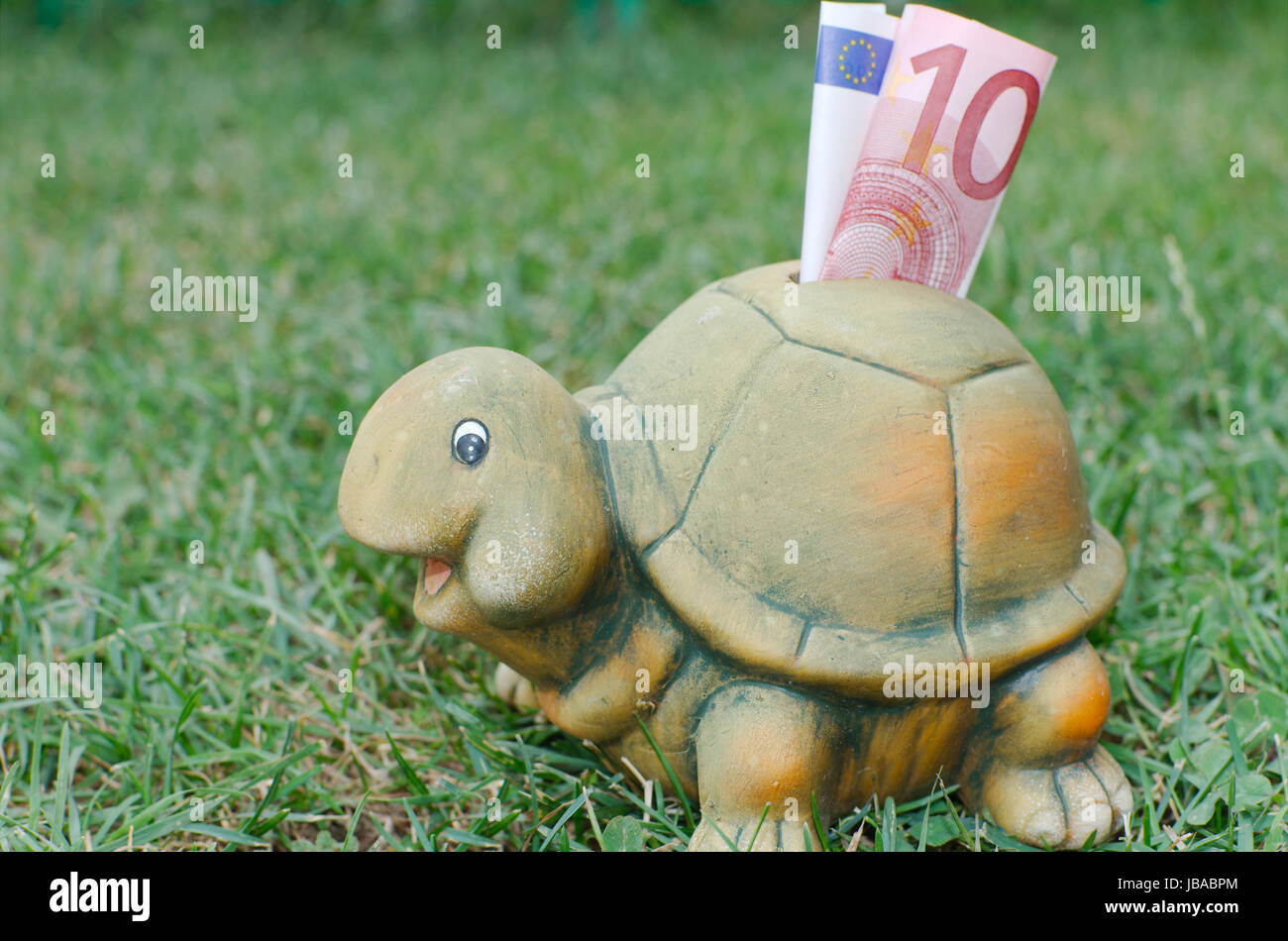Happy Turtle Piggy Bank with Ten Euro Banknote in the Green Grass Stock ...