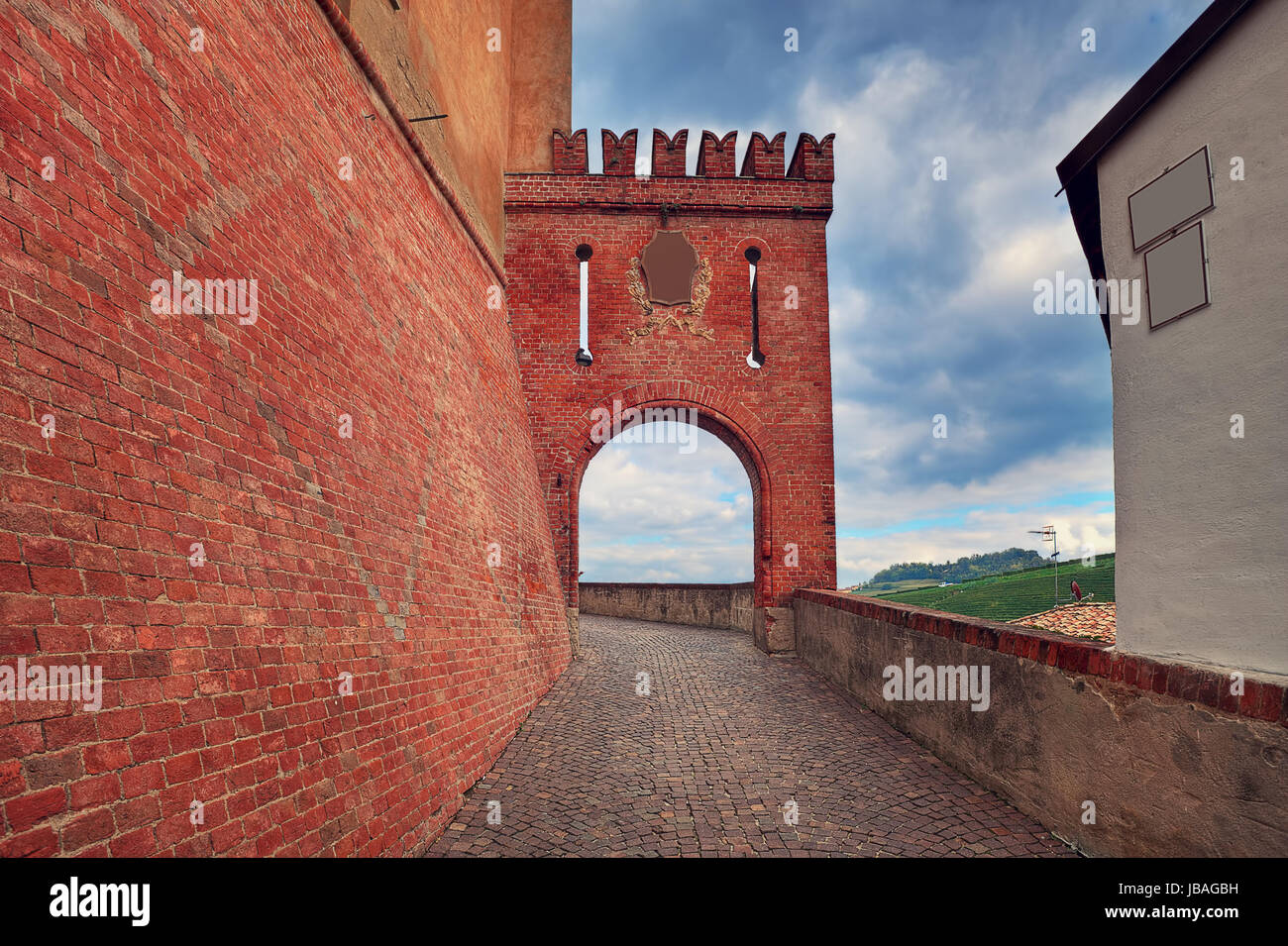 Narrow cobbled street along red brick wall and fragment of medieval ...