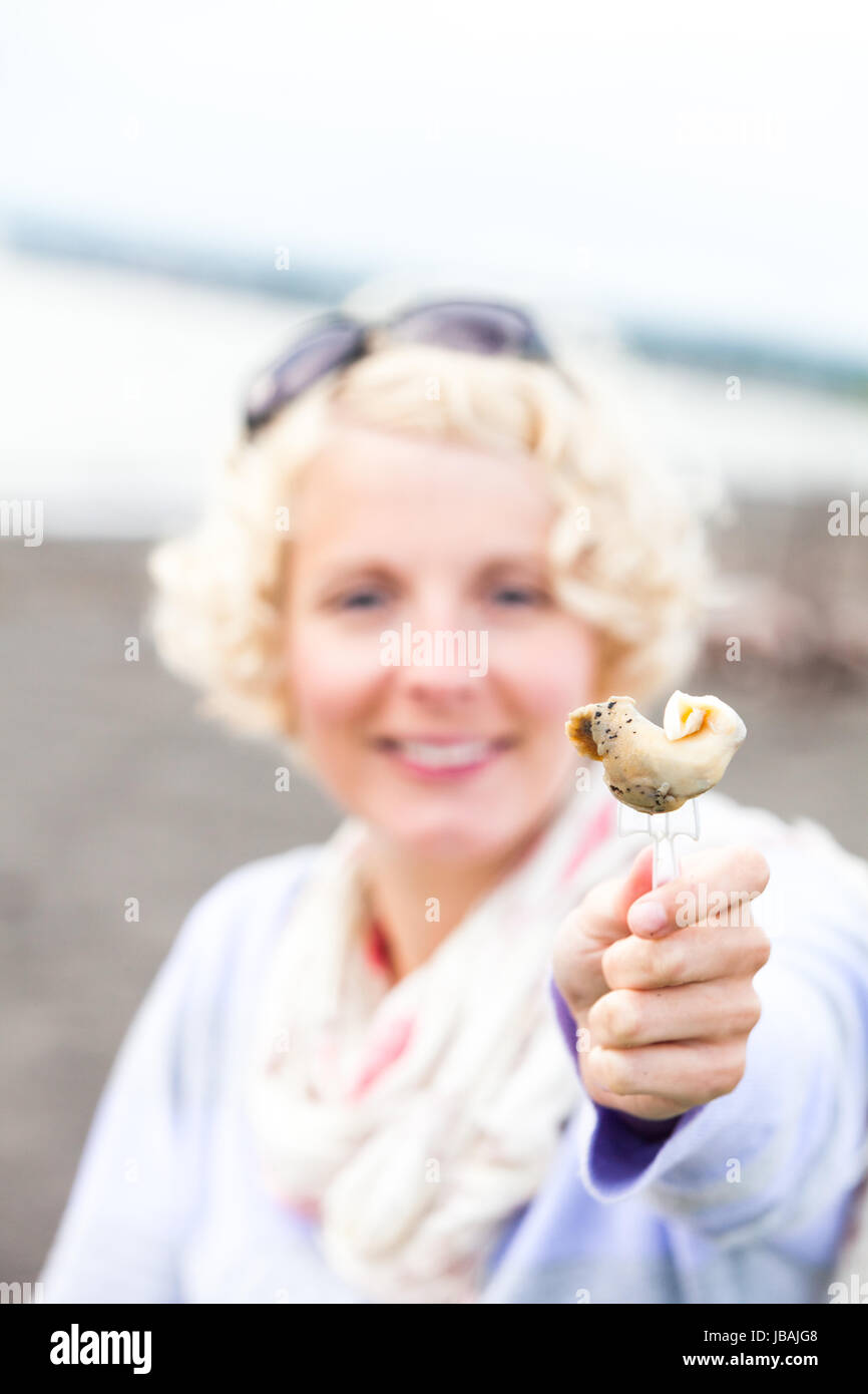 Young Woman Eating a prepared and out of the shell Whelk (bourgot in ...
