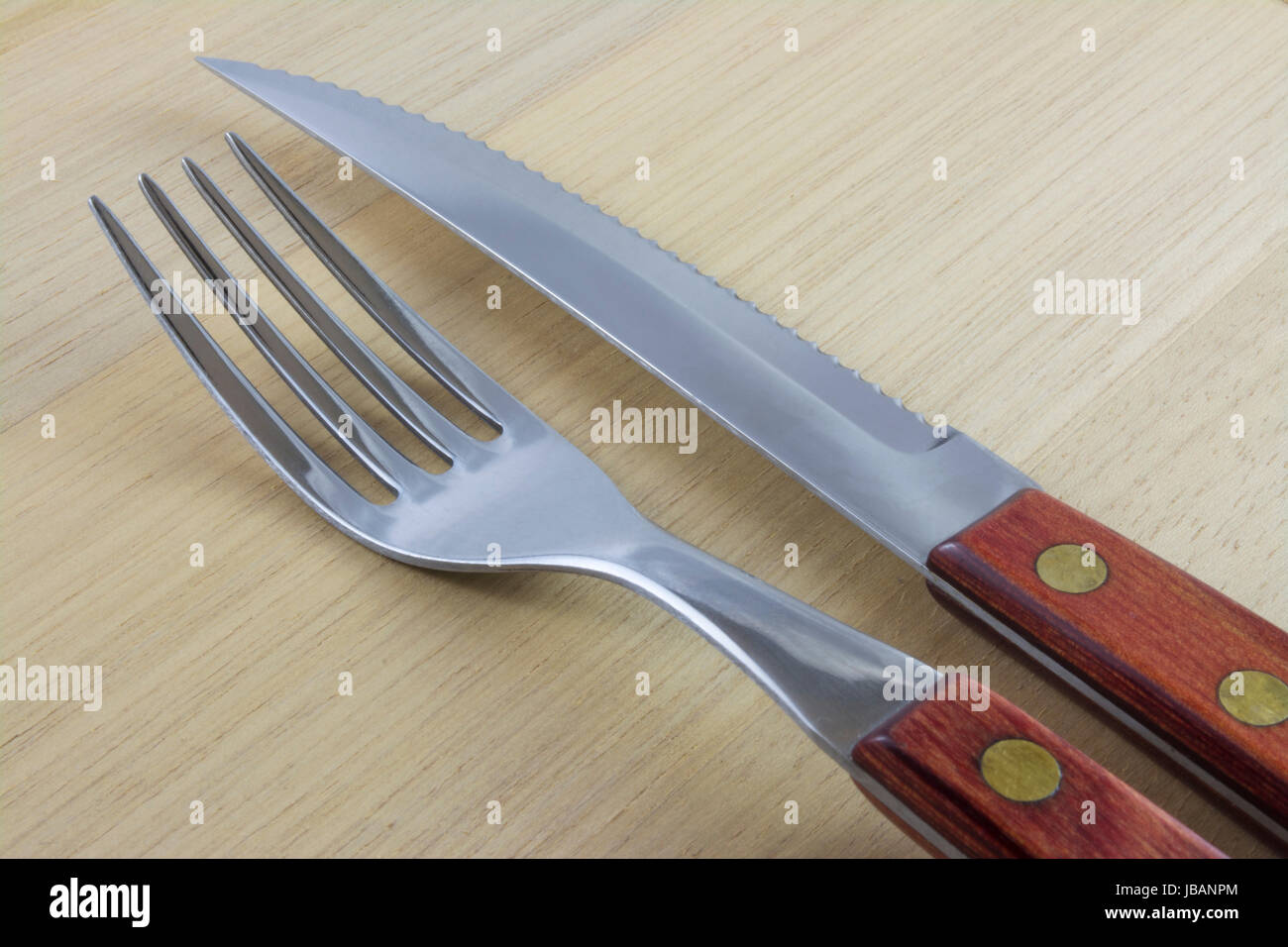 Fork and knife with red wooden handle on a plate of natural wood Stock ...