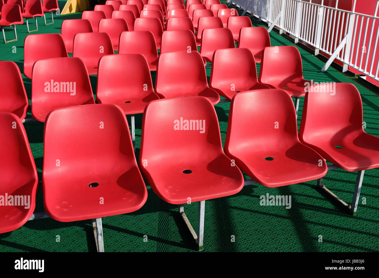 Rows of bright red plastic seating on a green rubber flooring Stock ...