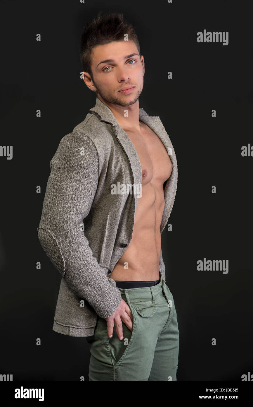 Confident, attractive young man with open jacket on muscular torso ...
