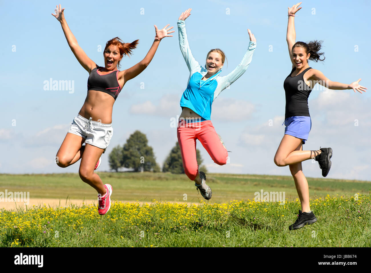 Sportive friends jumping cheerful on sunny meadow teenage girls Stock ...
