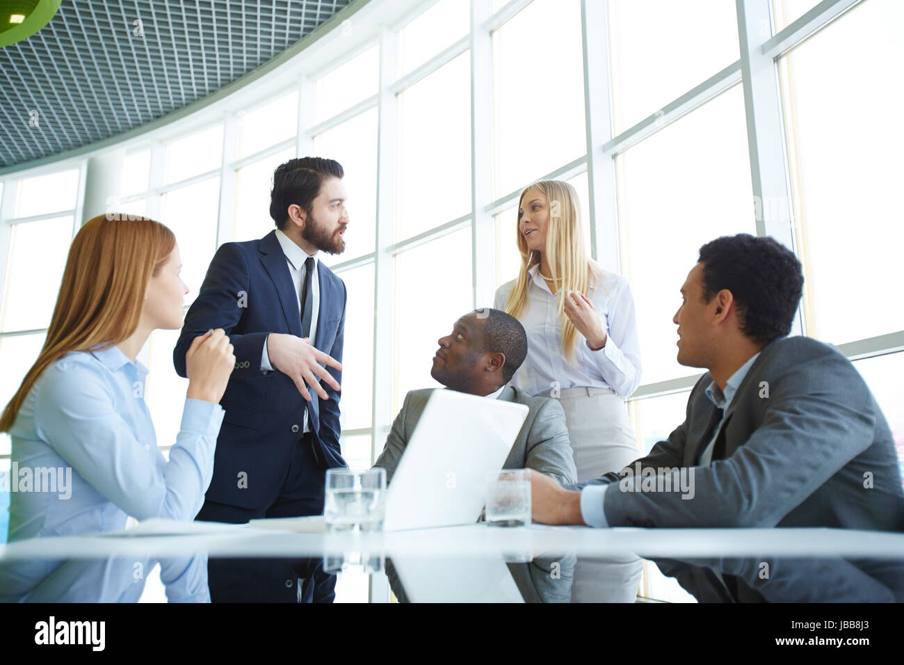 Group of business partners looking at their boss explaining his idea to ...