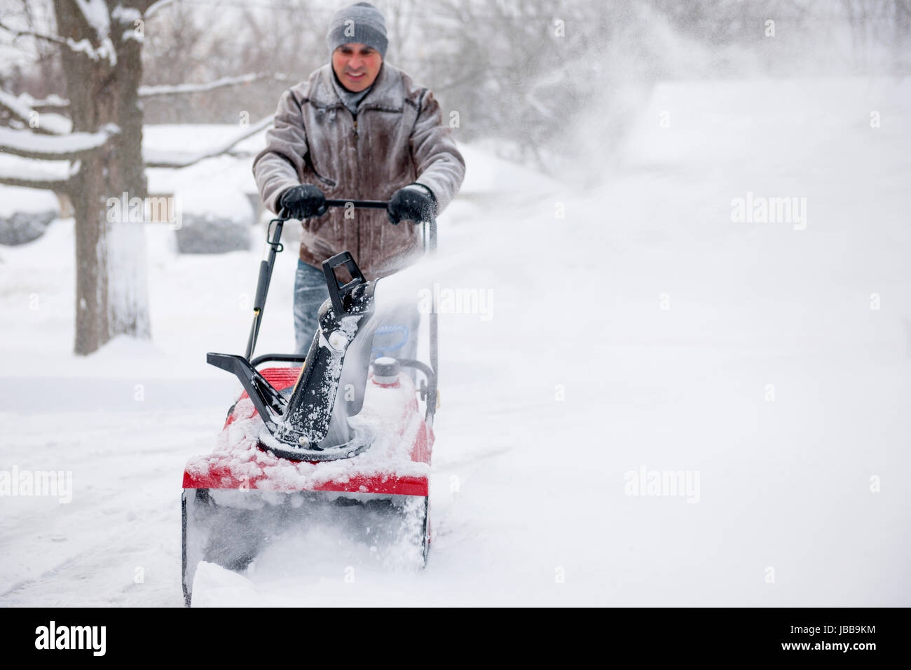 Man using snowblower to clear deep snow on residential driveway after ...