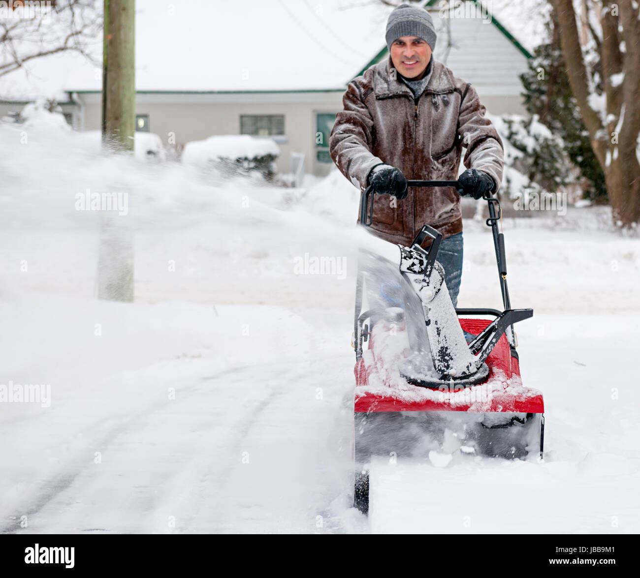 Man using snowblower to clear deep snow on residential driveway after ...