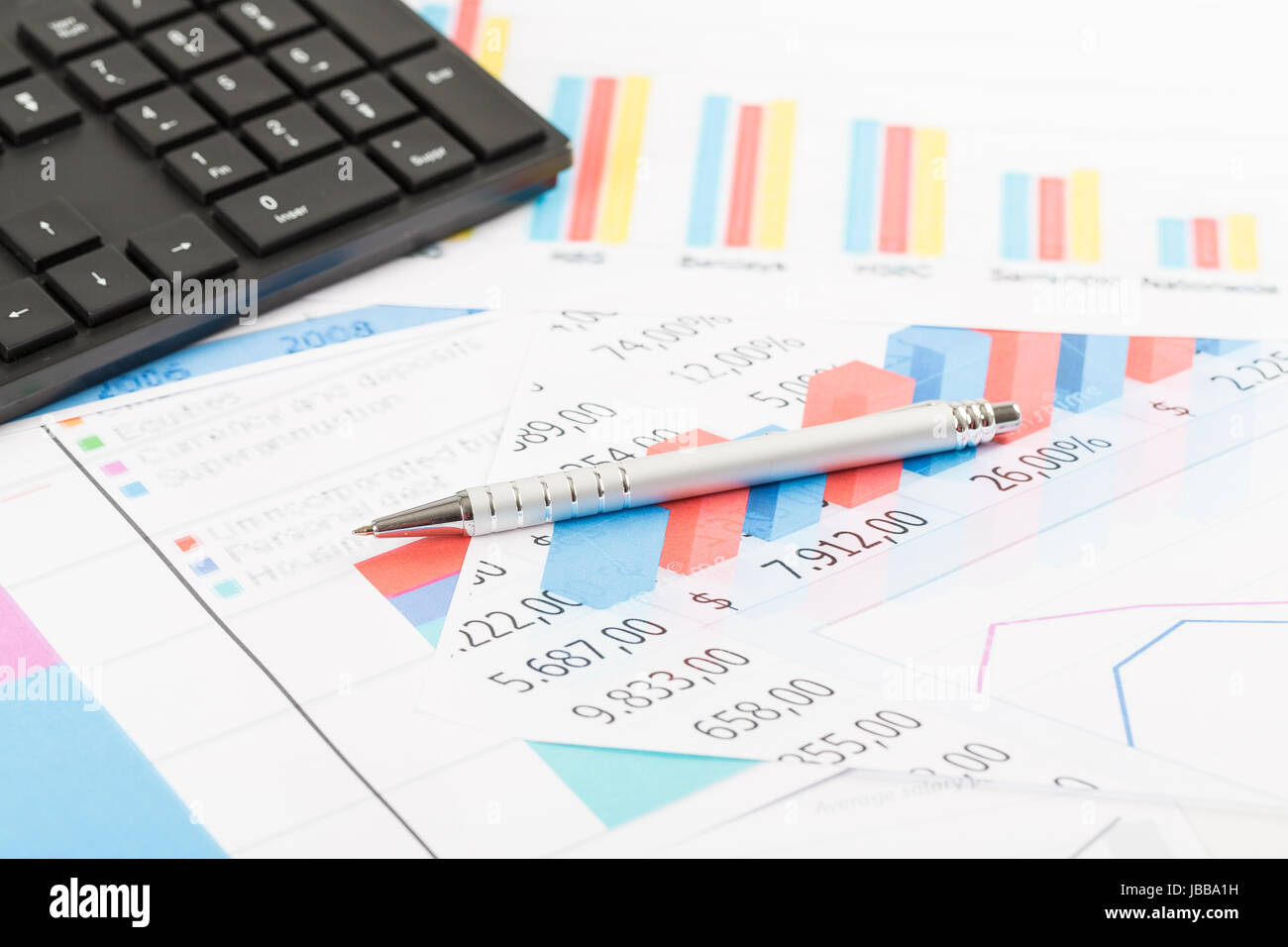 Financial printed paper charts, graphs on desk with pen and keyboard ...