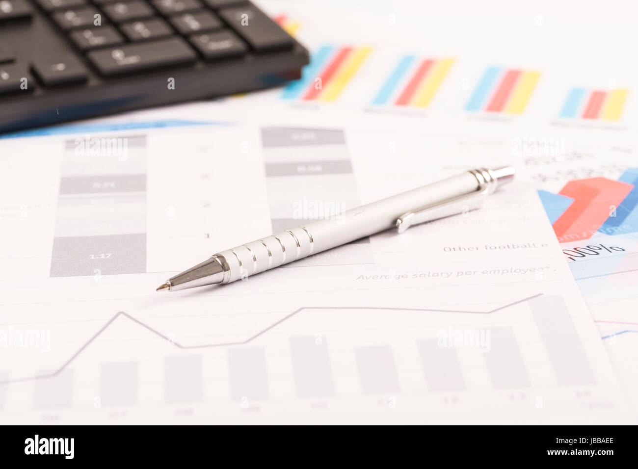 Financial printed paper charts, graphs on desk with pen and keyboard ...