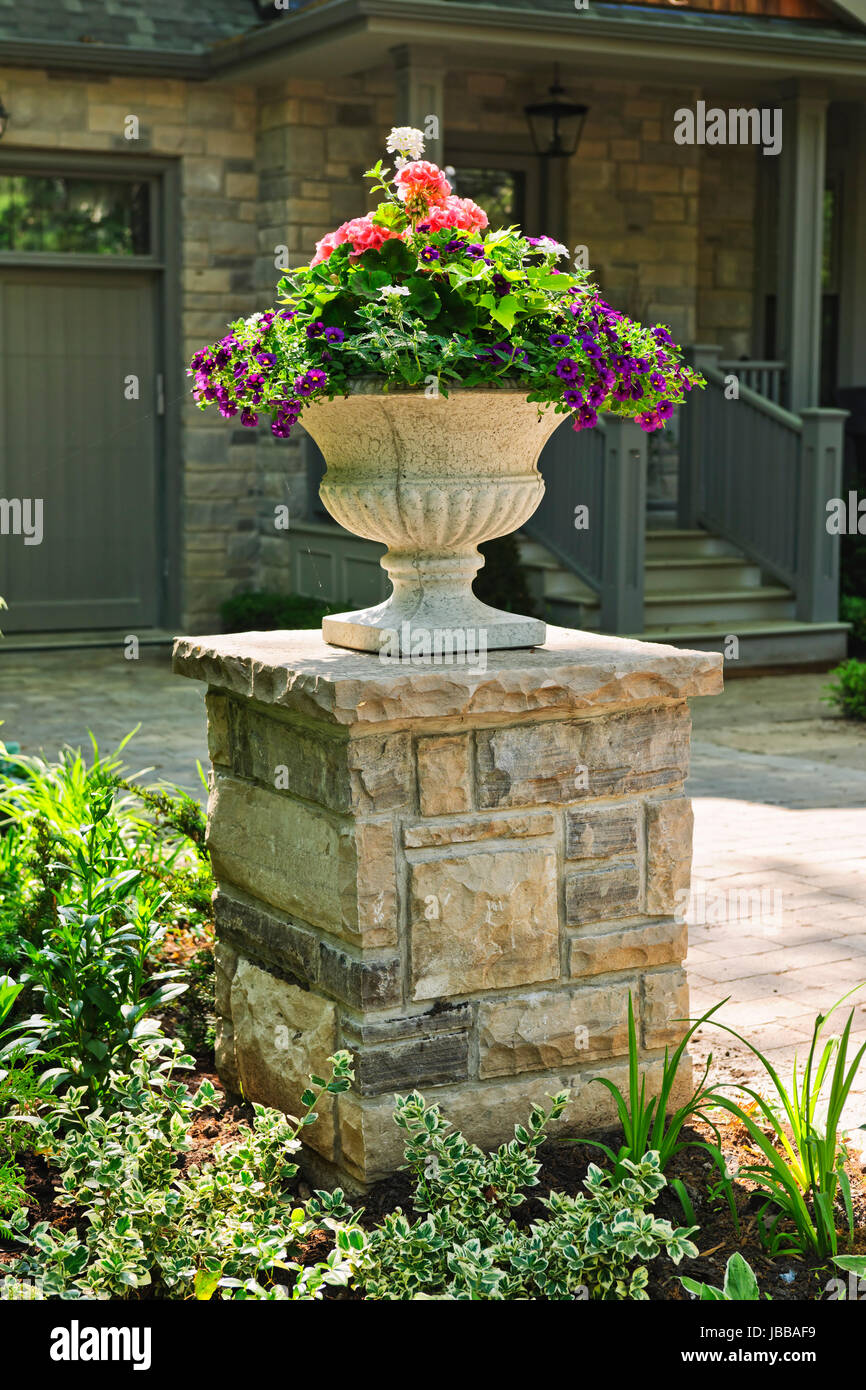 Stone planter with flowers near driveway of house Stock Photo - Alamy