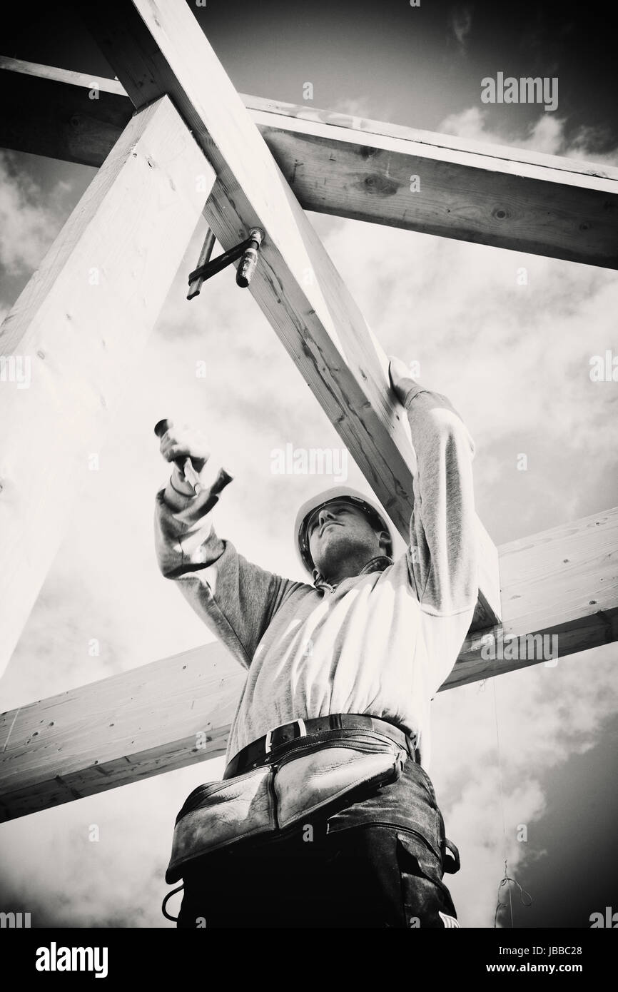 carpenter with hammer working on timber construction. Monochrome Stock ...
