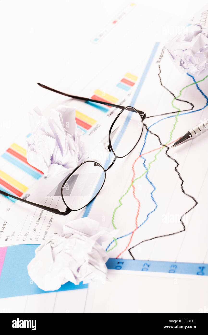 Desk with graphs, keyboard, glasses, pen and shredded papers. Stress at ...