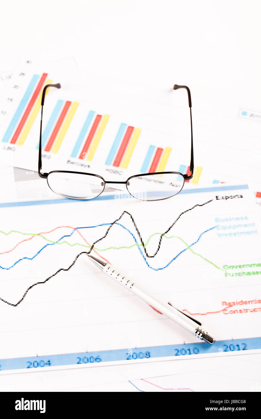 Financial analysis. Desk with graphs pen and glasses Stock Photo - Alamy