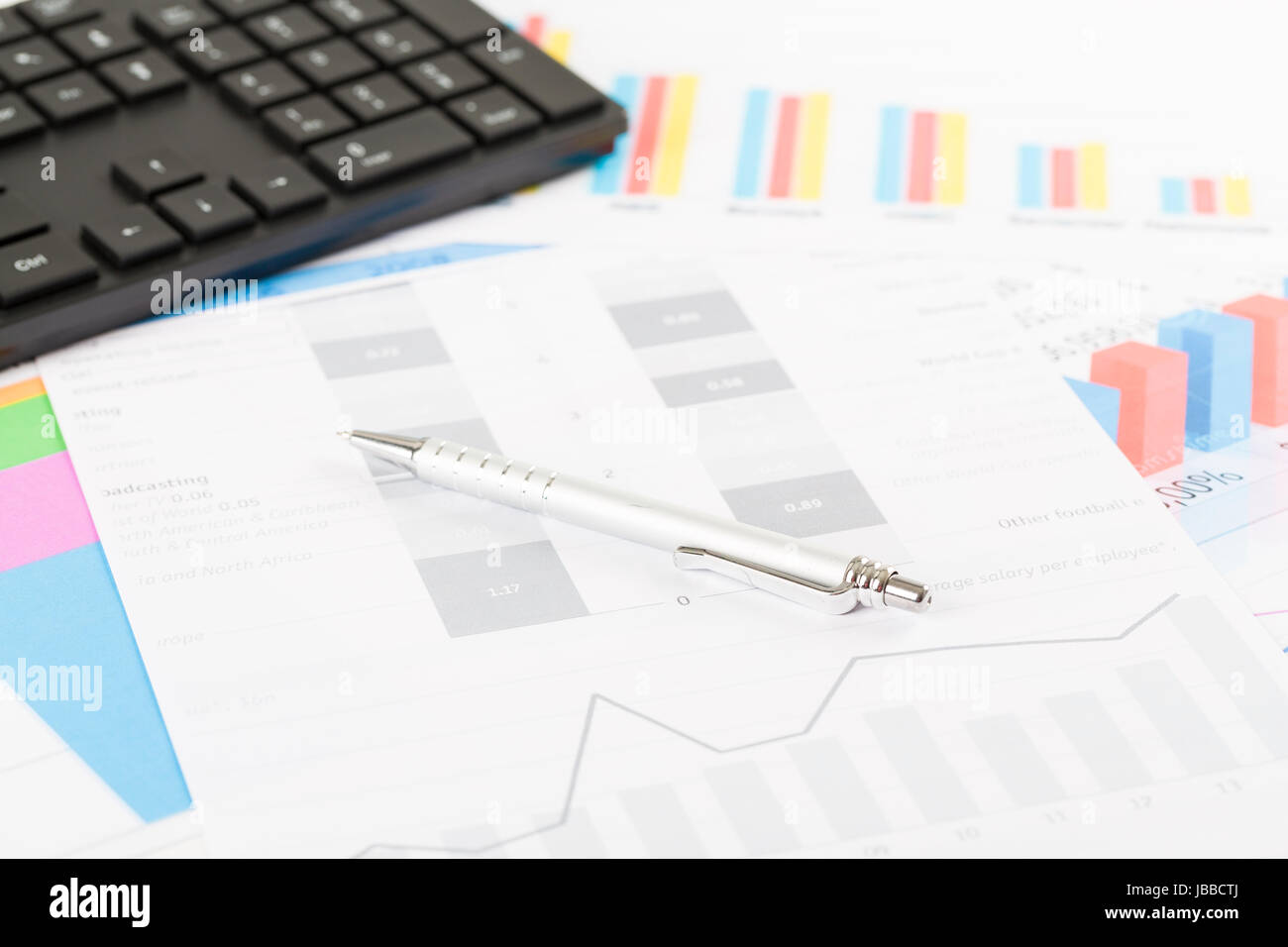 Financial printed paper charts, graphs on desk with pen and keyboard ...