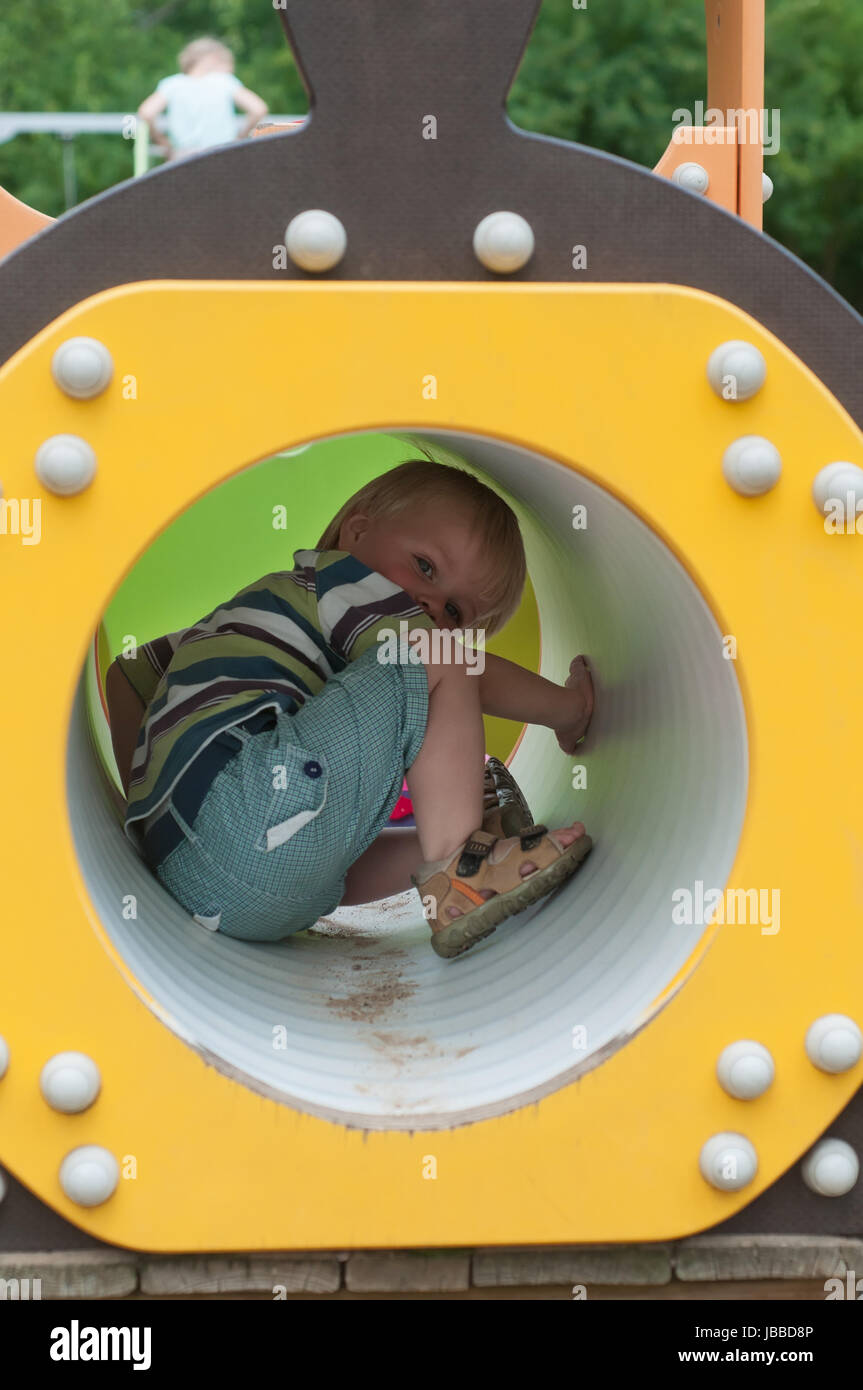 Young boy sitting in crawl tube on the playground Stock Photo - Alamy