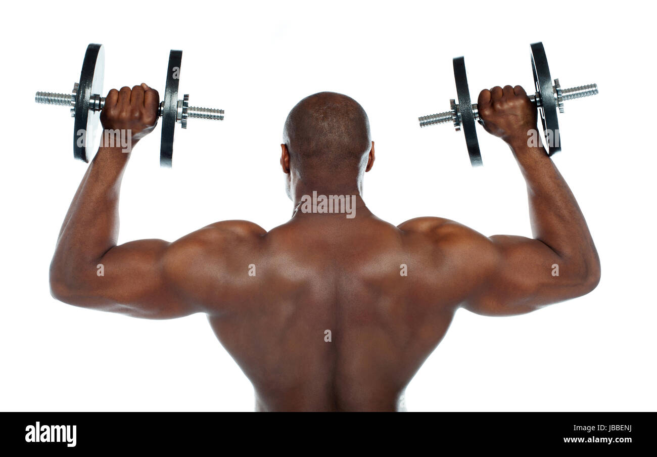 Rear view of a young male bodybuilder doing heavy weight exercise with ...