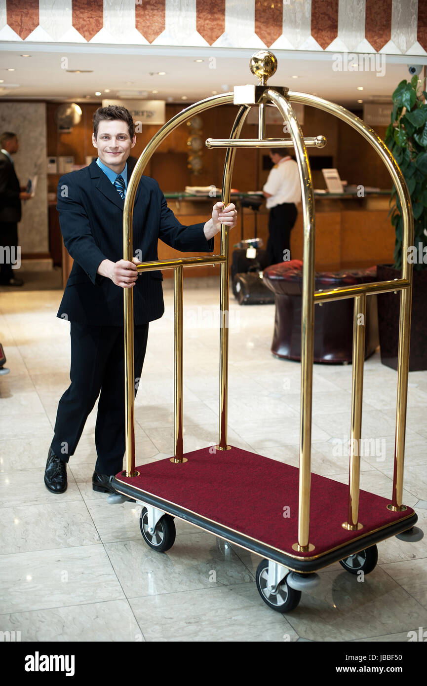 Casual shot of a concierge pushing the cart in hotel lobby Stock Photo ...