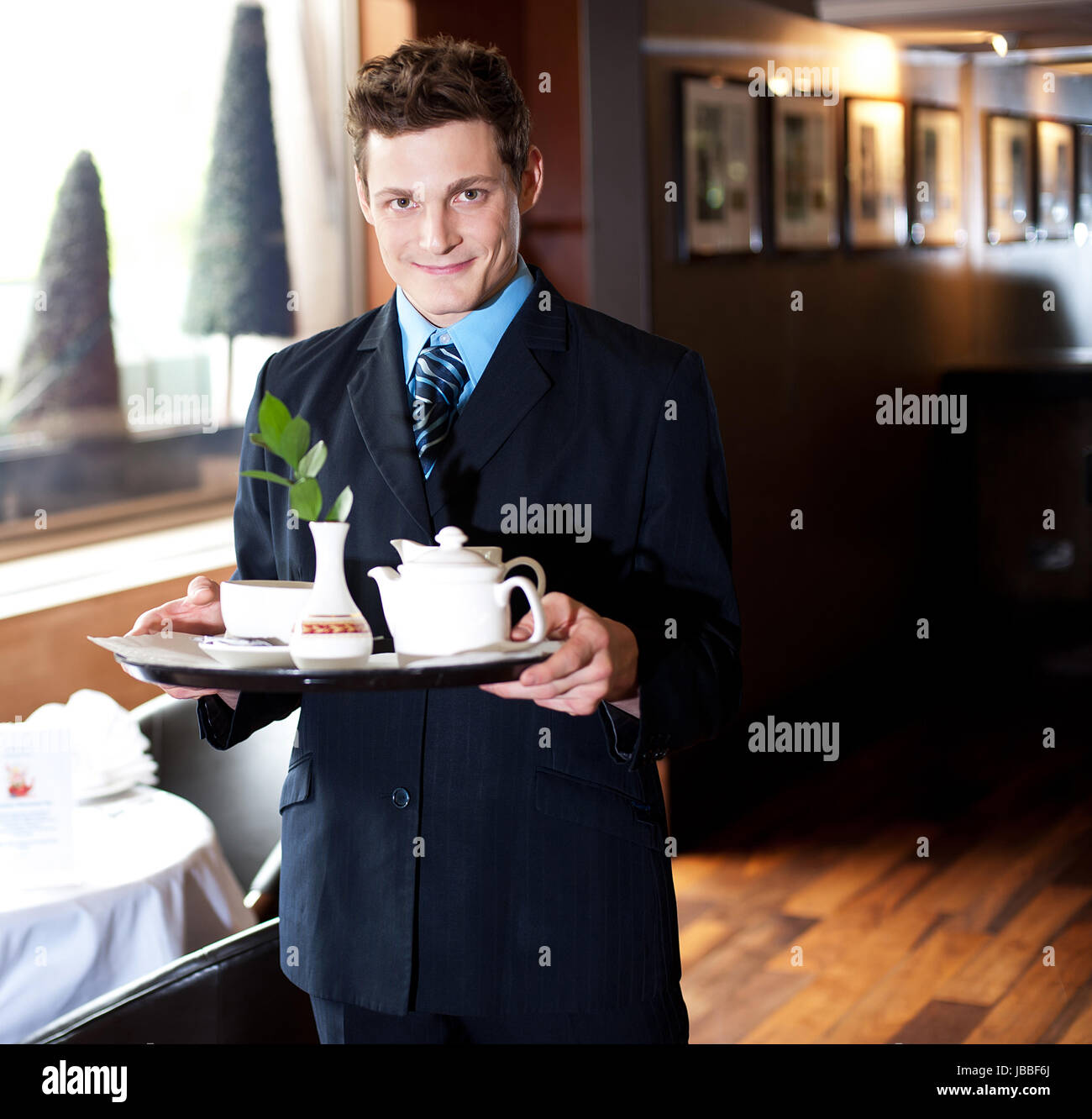 Good looking host in a restaurant holding tea tray for guests Stock ...