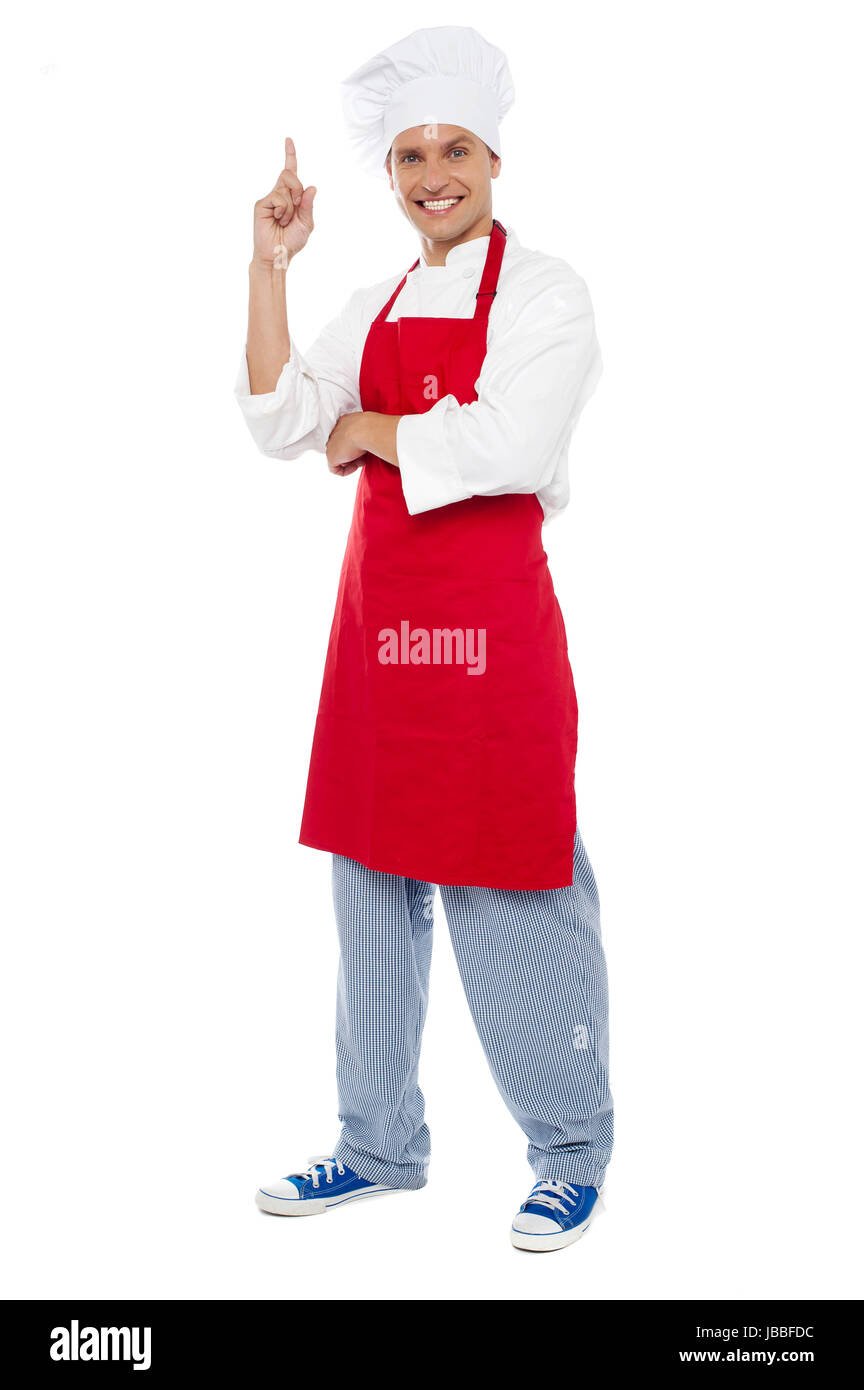 Young smart chef pointing index finger upwards. Full length portrait ...