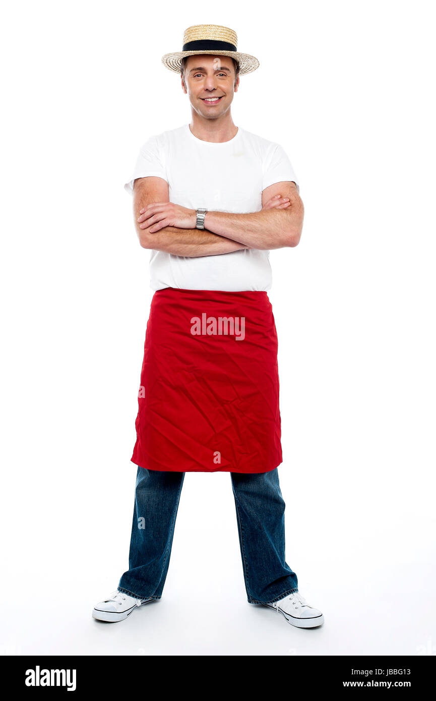 Stylish chap wearing hat. Apron tied on his waist. Arms folded, full ...