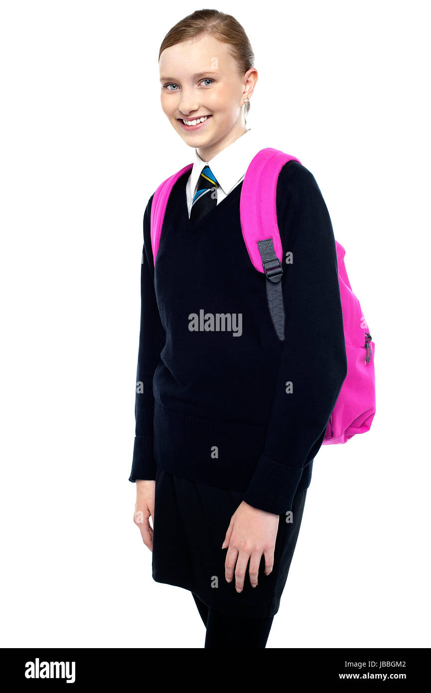 Casual shot of a cheerful girl in school uniform carrying backpack ...